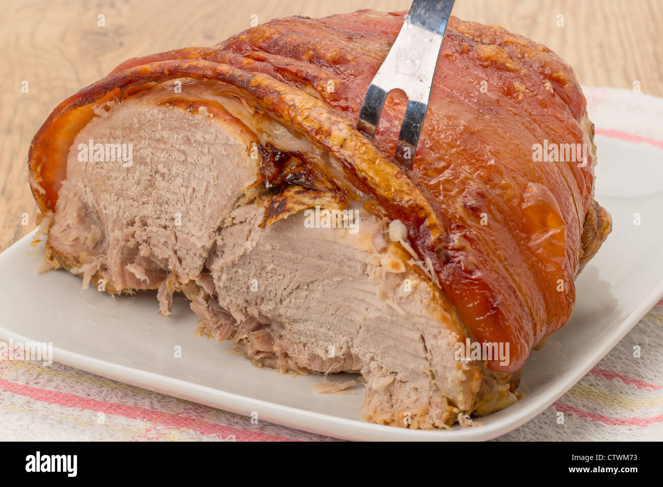 A roast pork joint on a white plate - studio shot Stock Photo - Alamy