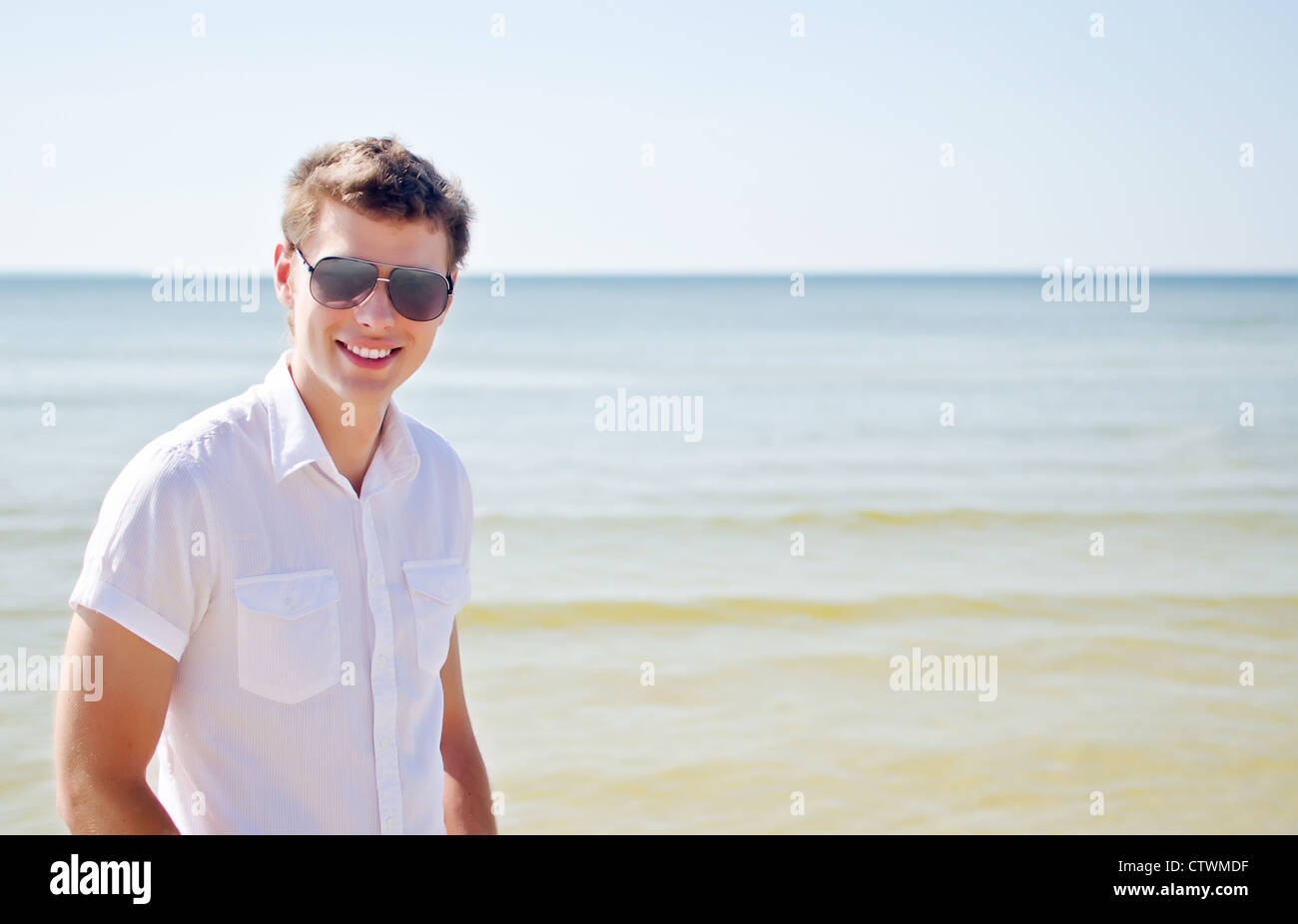 Handsome smiling guy on the beach, with the sea in the background Stock ...