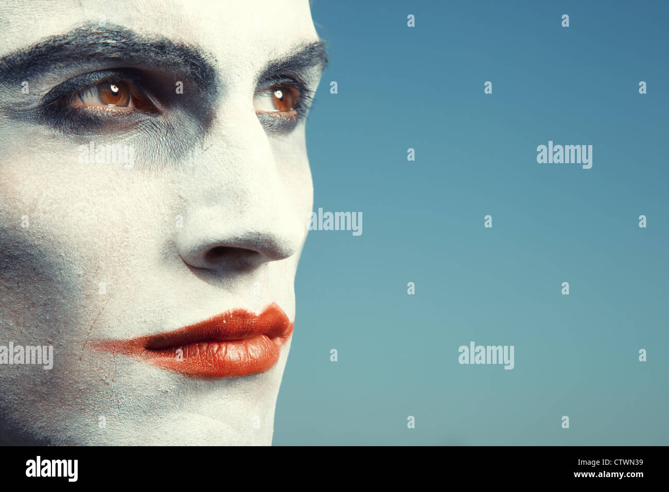 Sad clown with makeup on a blue background Stock Photo - Alamy
