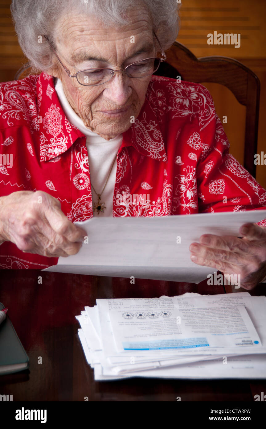 Elderly woman reading through bills and financial paperwork Stock Photo ...
