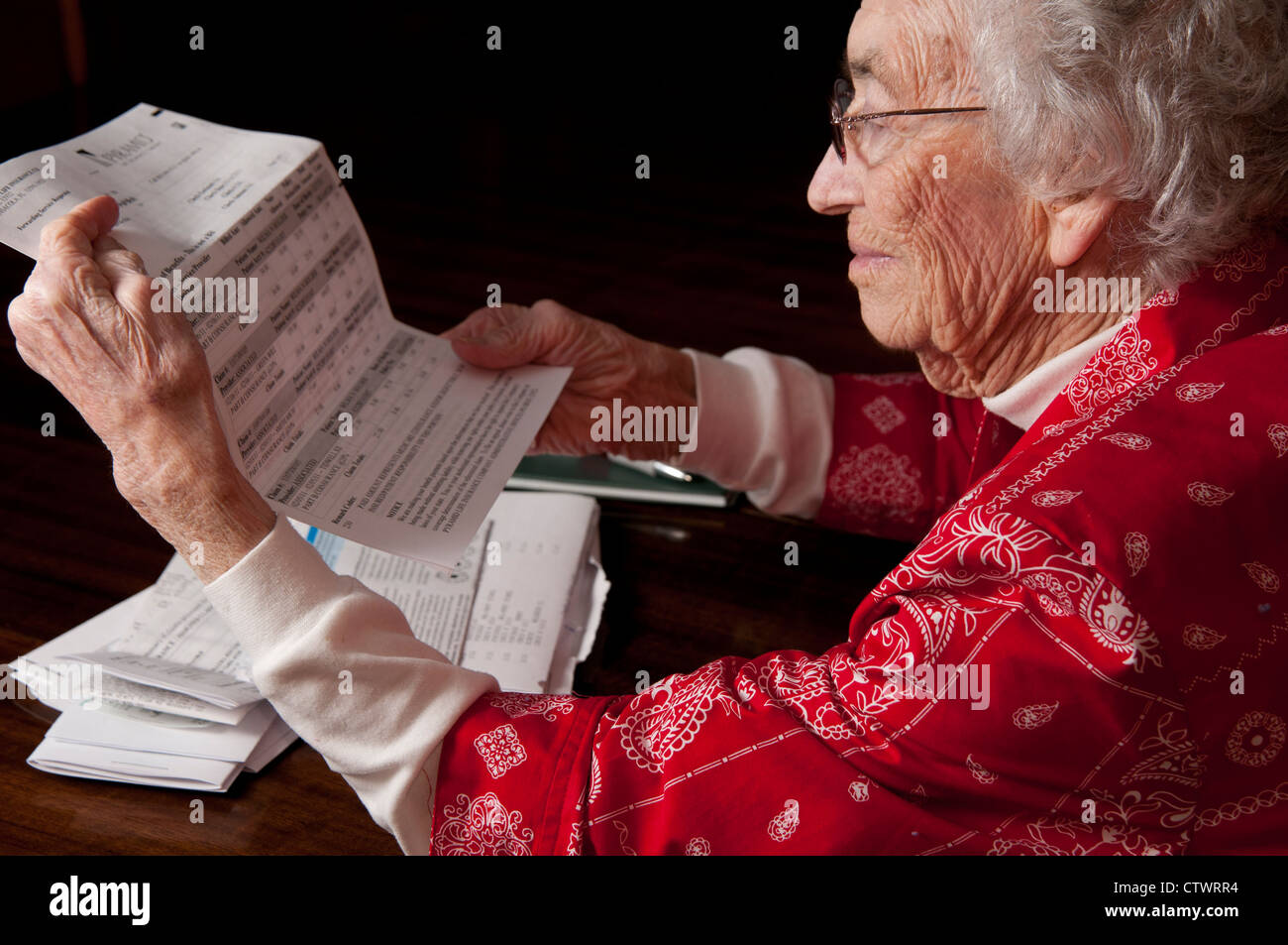 Elderly woman reading through bills and financial paperwork Stock Photo ...