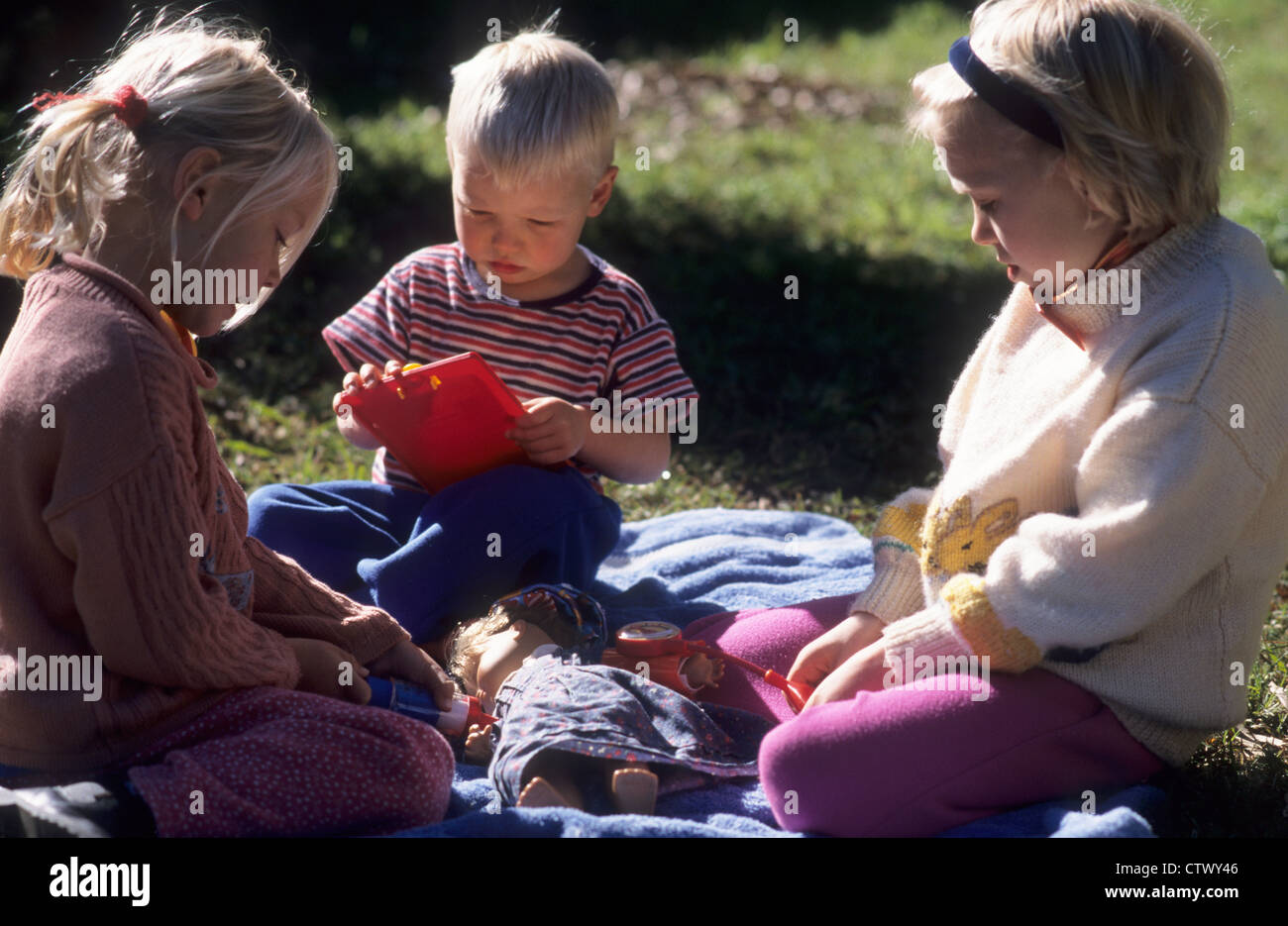 Three siblings playing together on the grass Stock Photo - Alamy