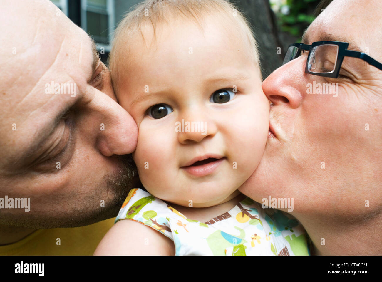 Parents kissing their baby Stock Photo - Alamy
