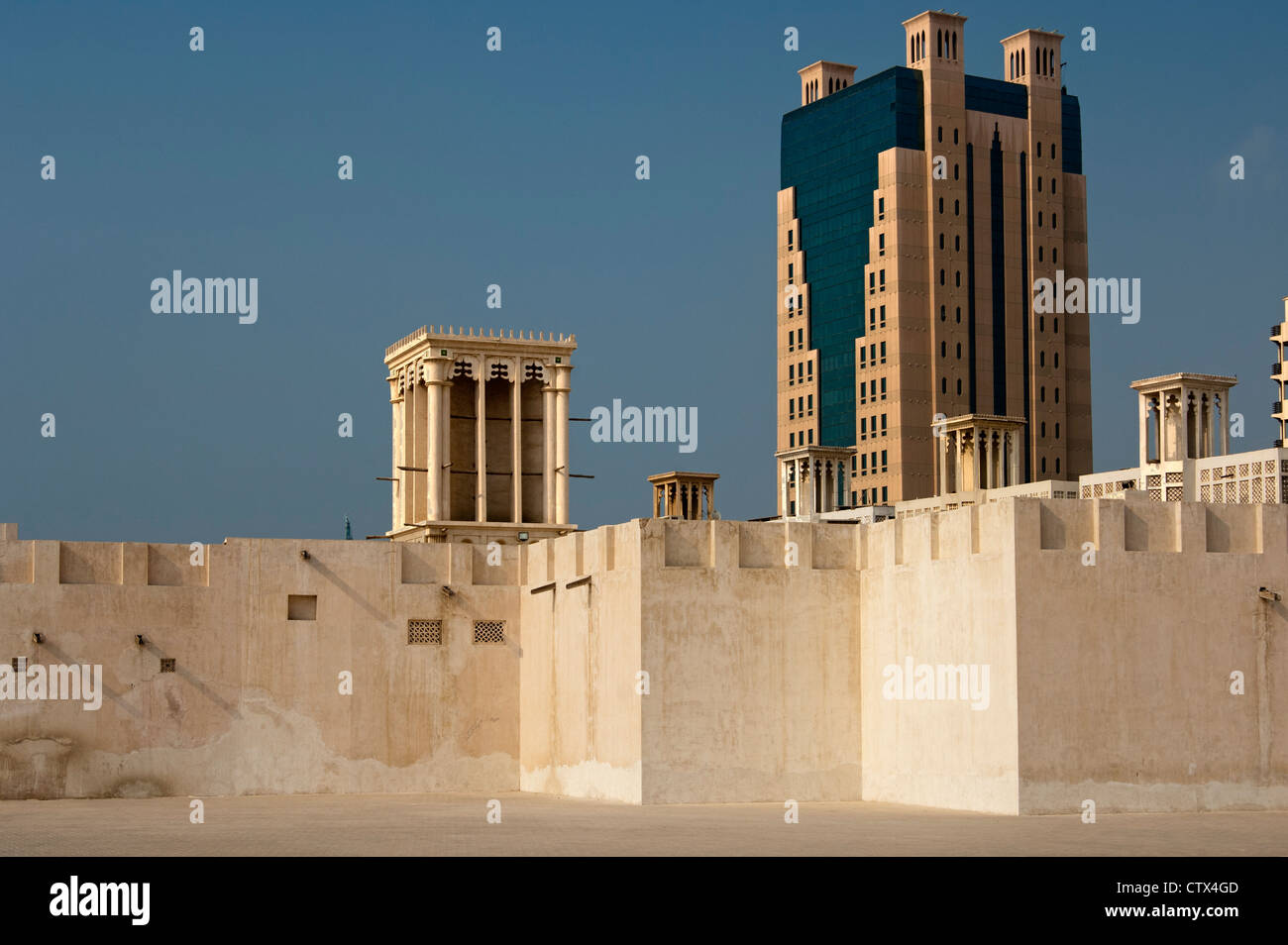 Modern skyscrapers rise above historical buildings with wind towers in ...