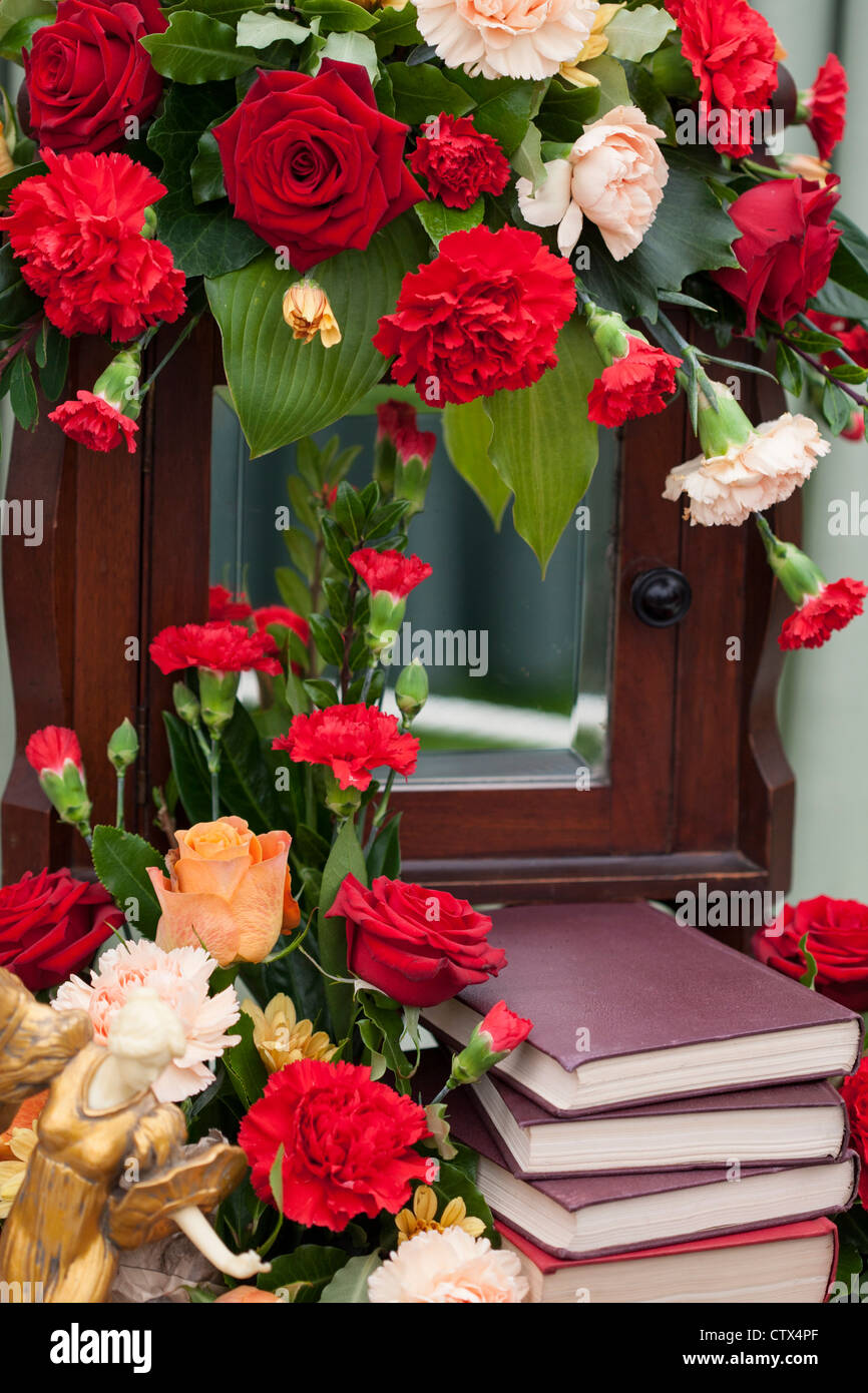 a floral display with a mirror and books Stock Photo - Alamy