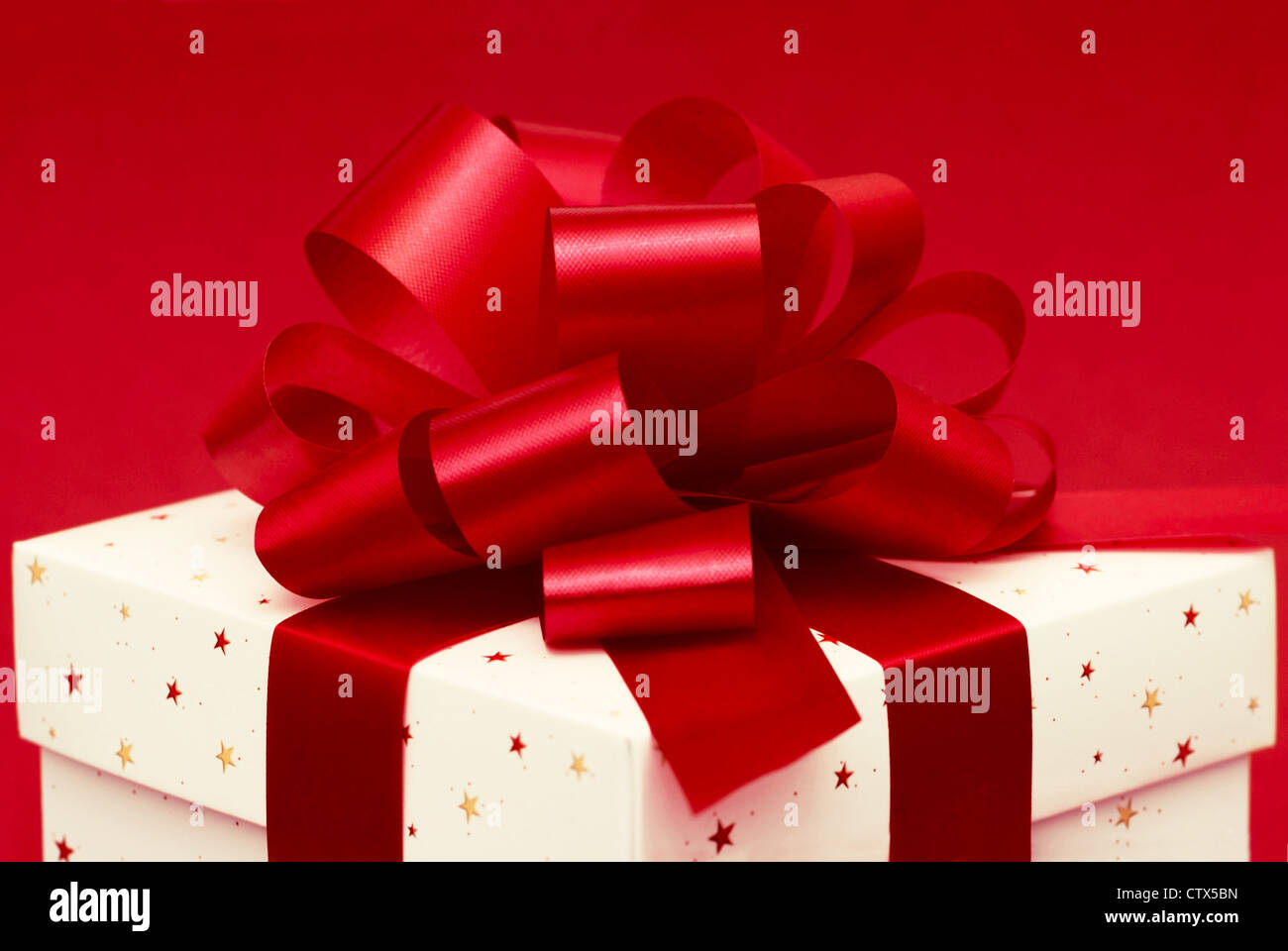 Christmas gift with red ribbon isolated on red Stock Photo - Alamy