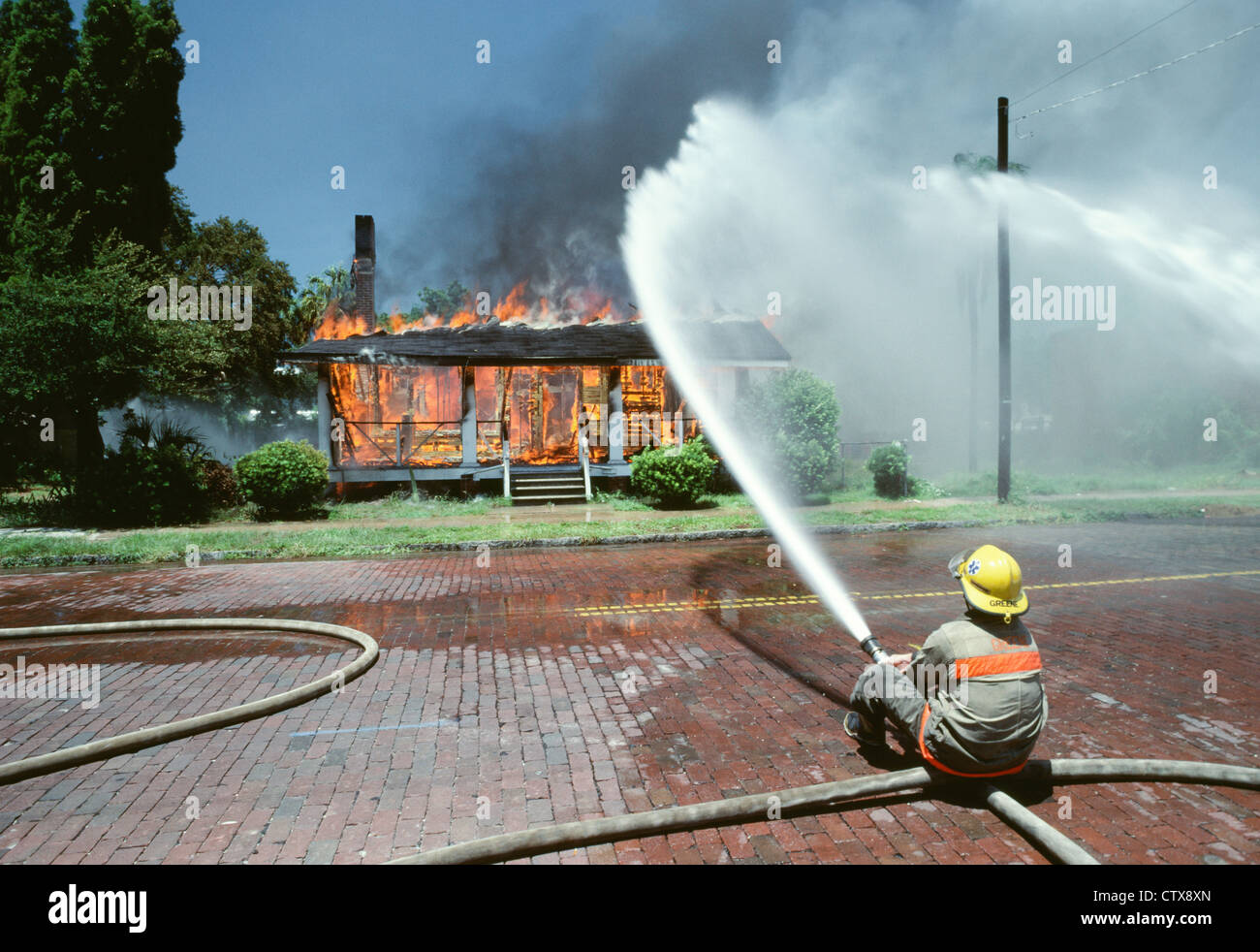 Fireman Spraying Wooden House Consumed in Flames Stock Photo - Alamy