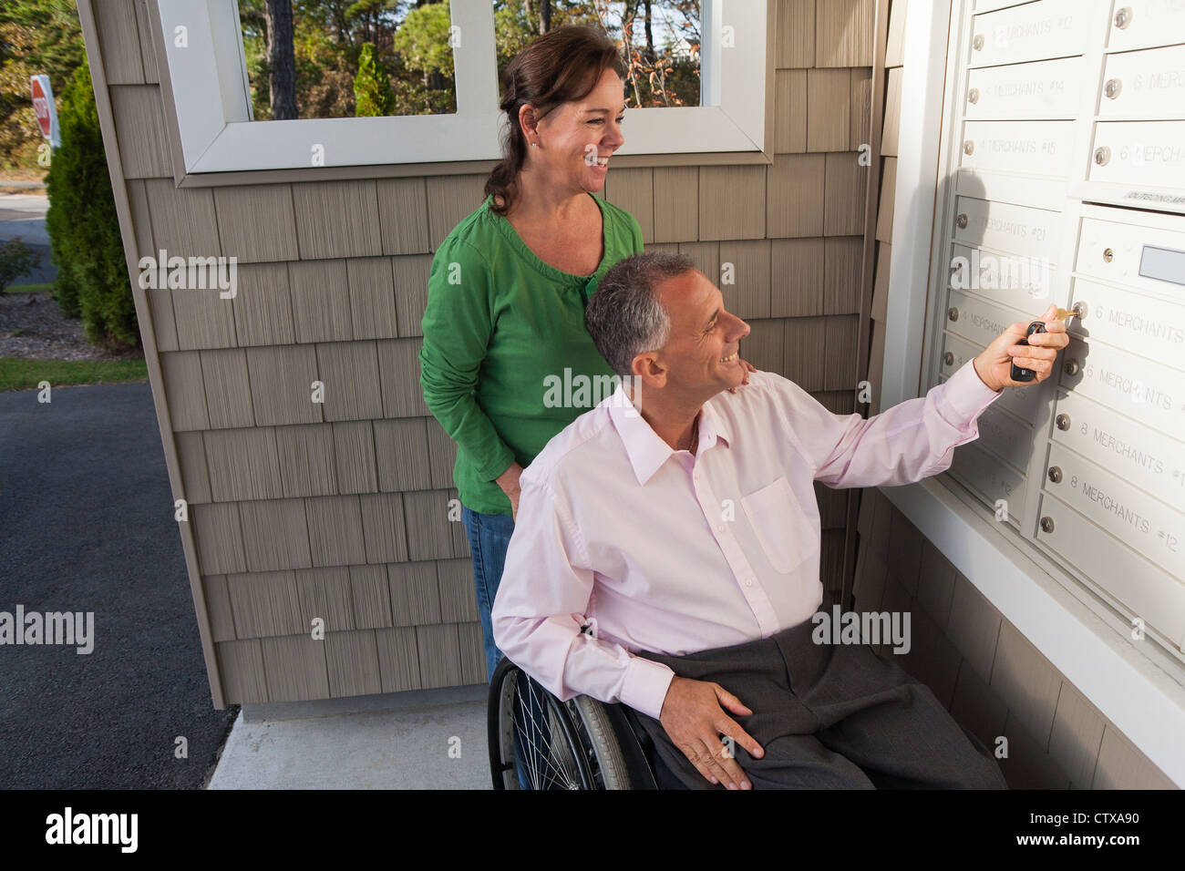 Man in wheelchair with wife getting mail from their new apartment ...