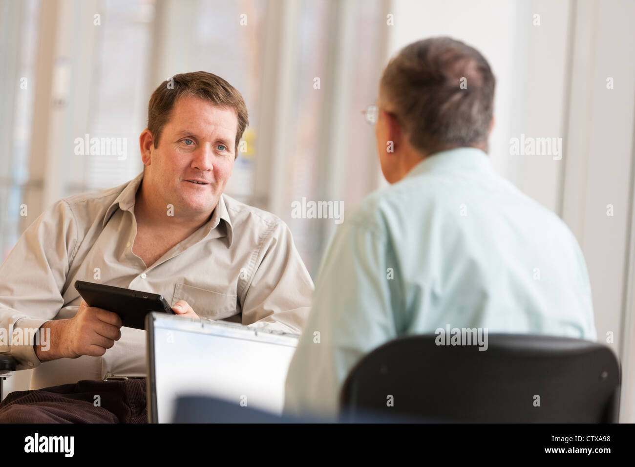 Man with spinal cord injury in wheelchair comparing a tablet with a ...