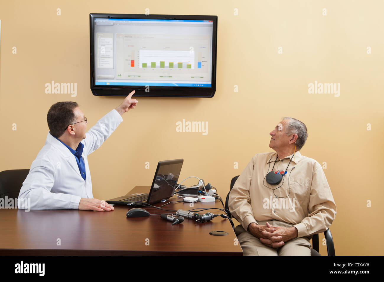 Audiologist explaining diagrams to a patient wearing hearing device ...