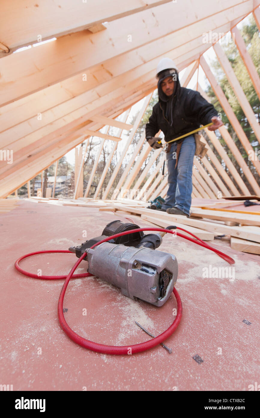 Close-up of a nail gun with a carpenter using measuring tape in the ...