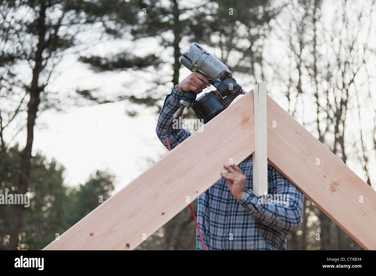 Carpenter nailing a rafter at peak Stock Photo - Alamy