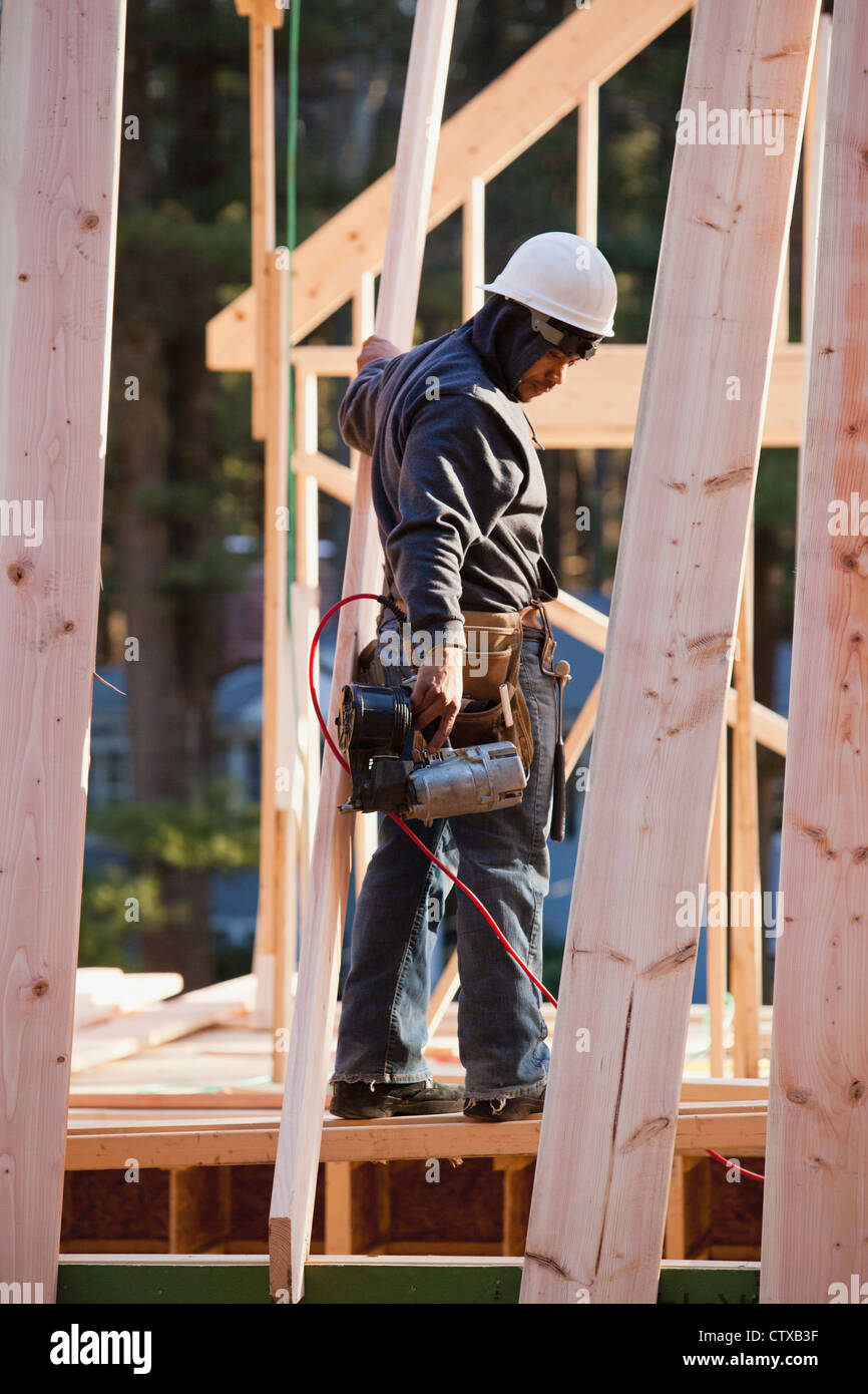 Carpenter with a nail gun working on rafters Stock Photo - Alamy