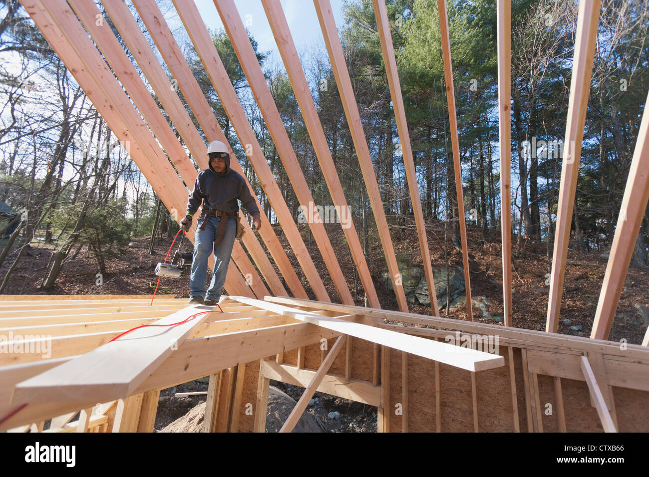 Carpenter walking on a rafter on floor joists Stock Photo - Alamy