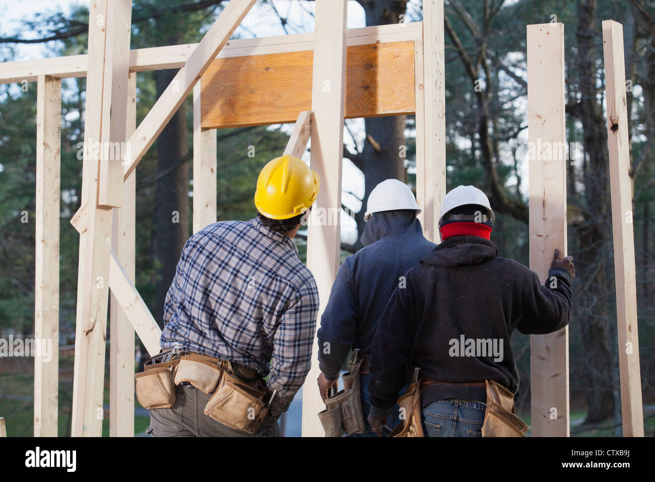 Carpenters preparing to frame exterior wall of a house under ...