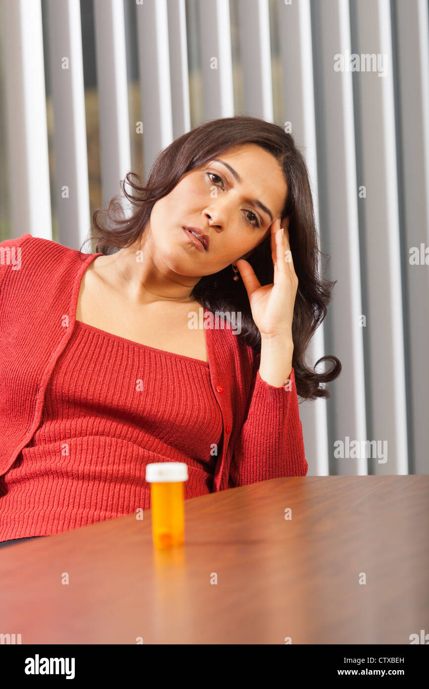 Businesswoman contemplating medicine at desk Stock Photo - Alamy