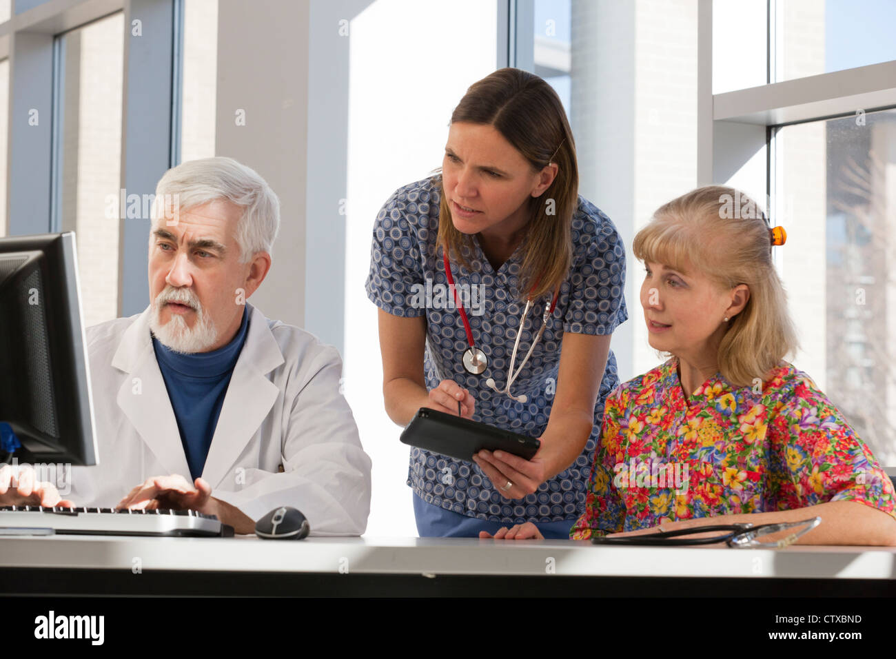 Two nurses and a doctor working on computer and tablet Stock Photo - Alamy