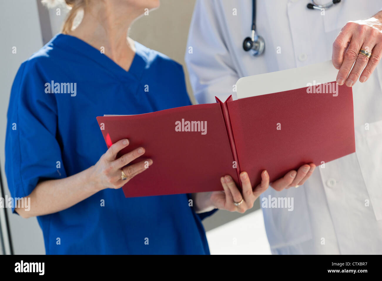 Doctor looking at files held by a nurse Stock Photo - Alamy