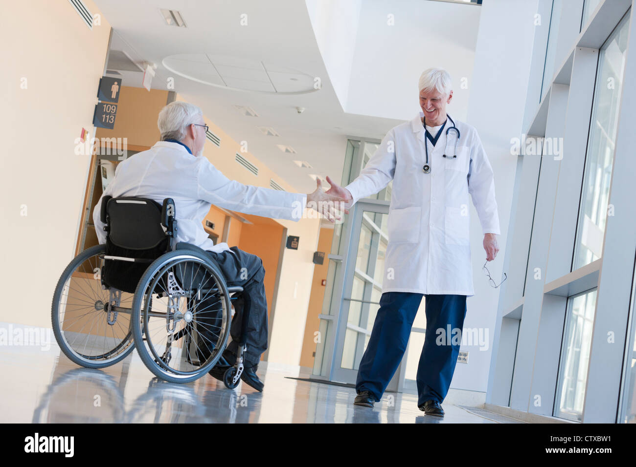 Doctor with muscular dystrophy in wheelchair shaking hands with another ...