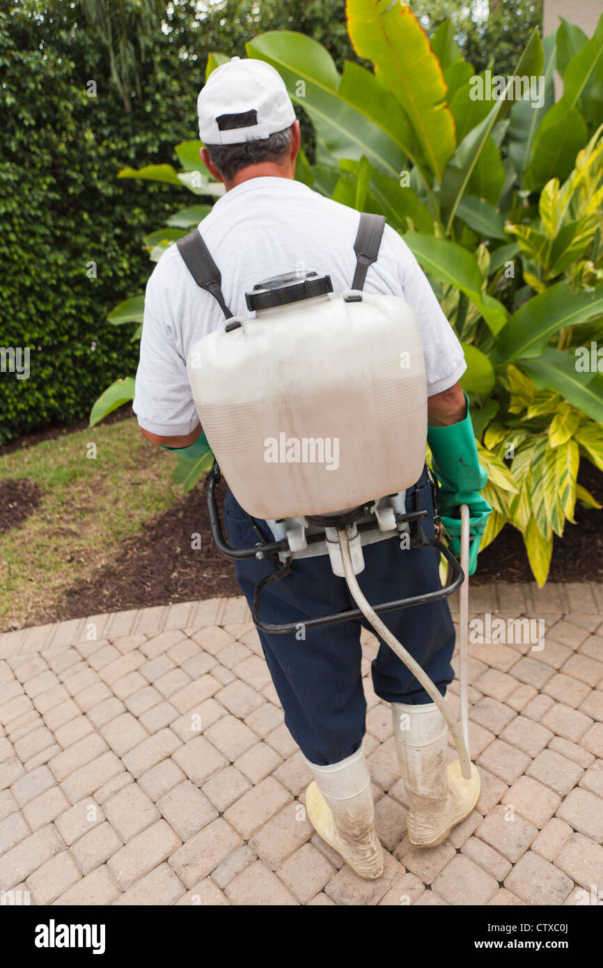 Pest control technician with portable spray rig using spray nozzle and ...