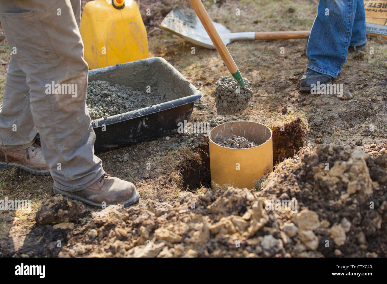 Hispanic carpenter adding cement to deck footing tube Stock Photo - Alamy