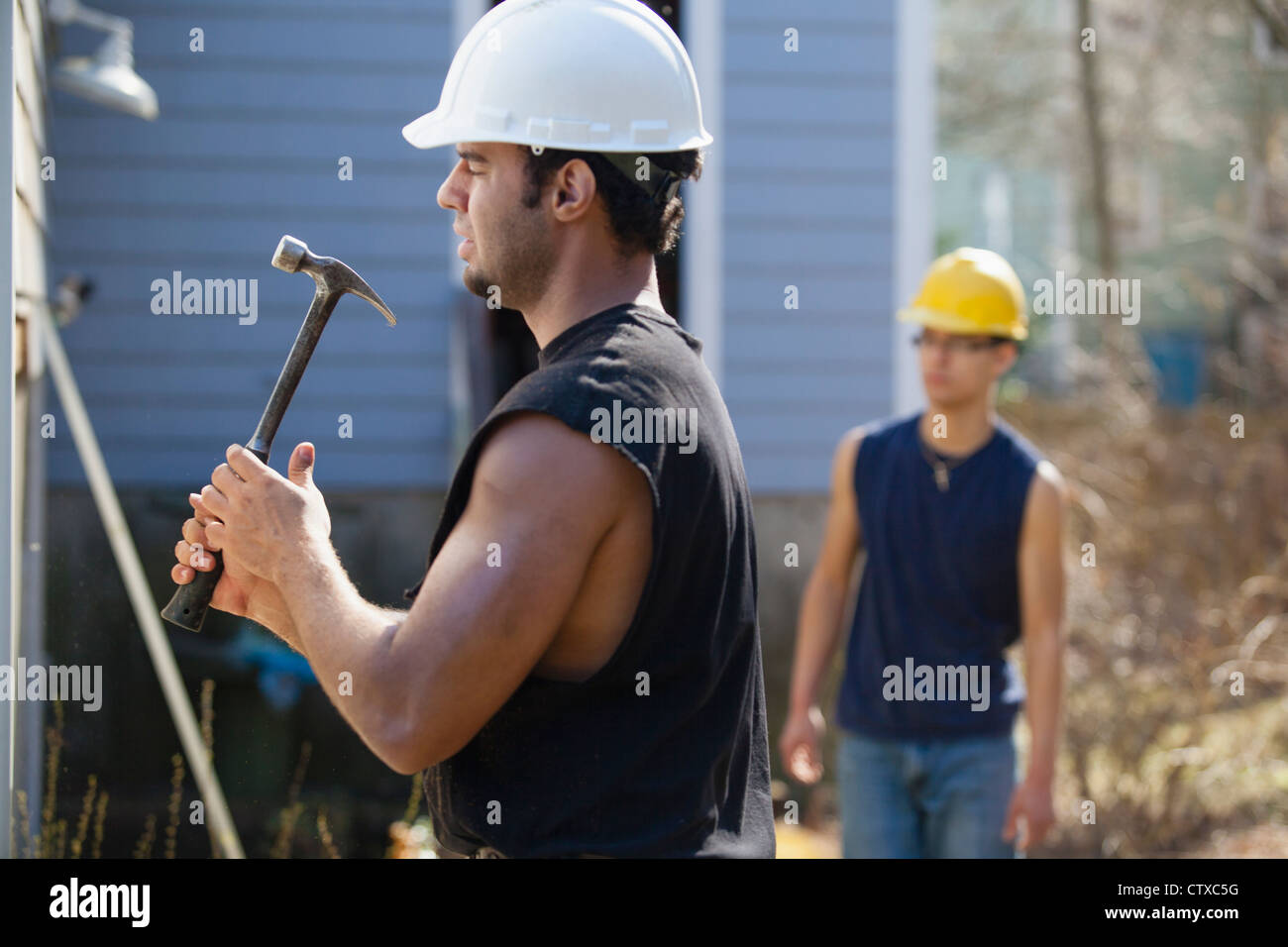 Hispanic carpenters preparing house siding for deck Stock Photo - Alamy