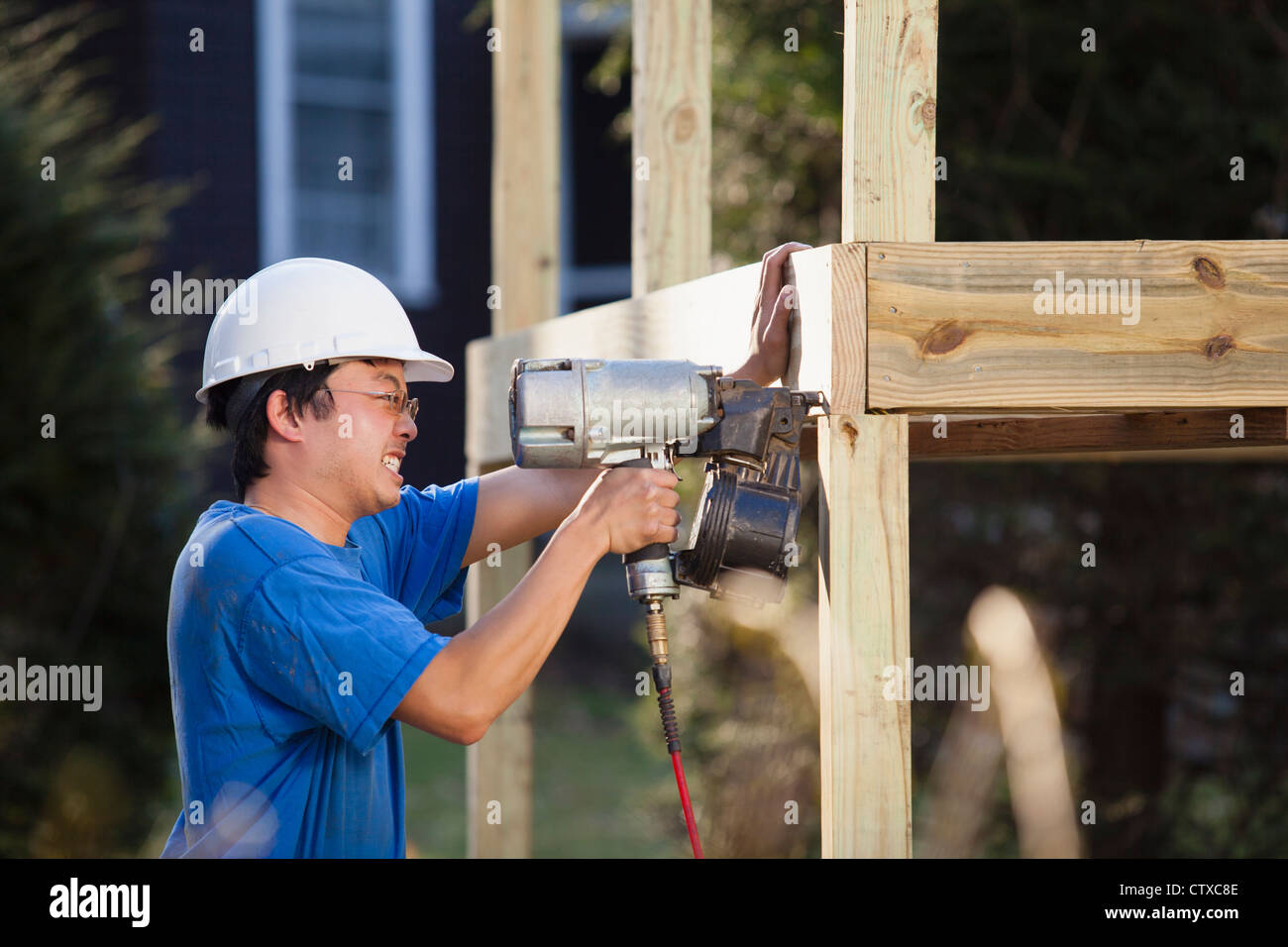 Carpenter using air gun to install deck framing Stock Photo - Alamy