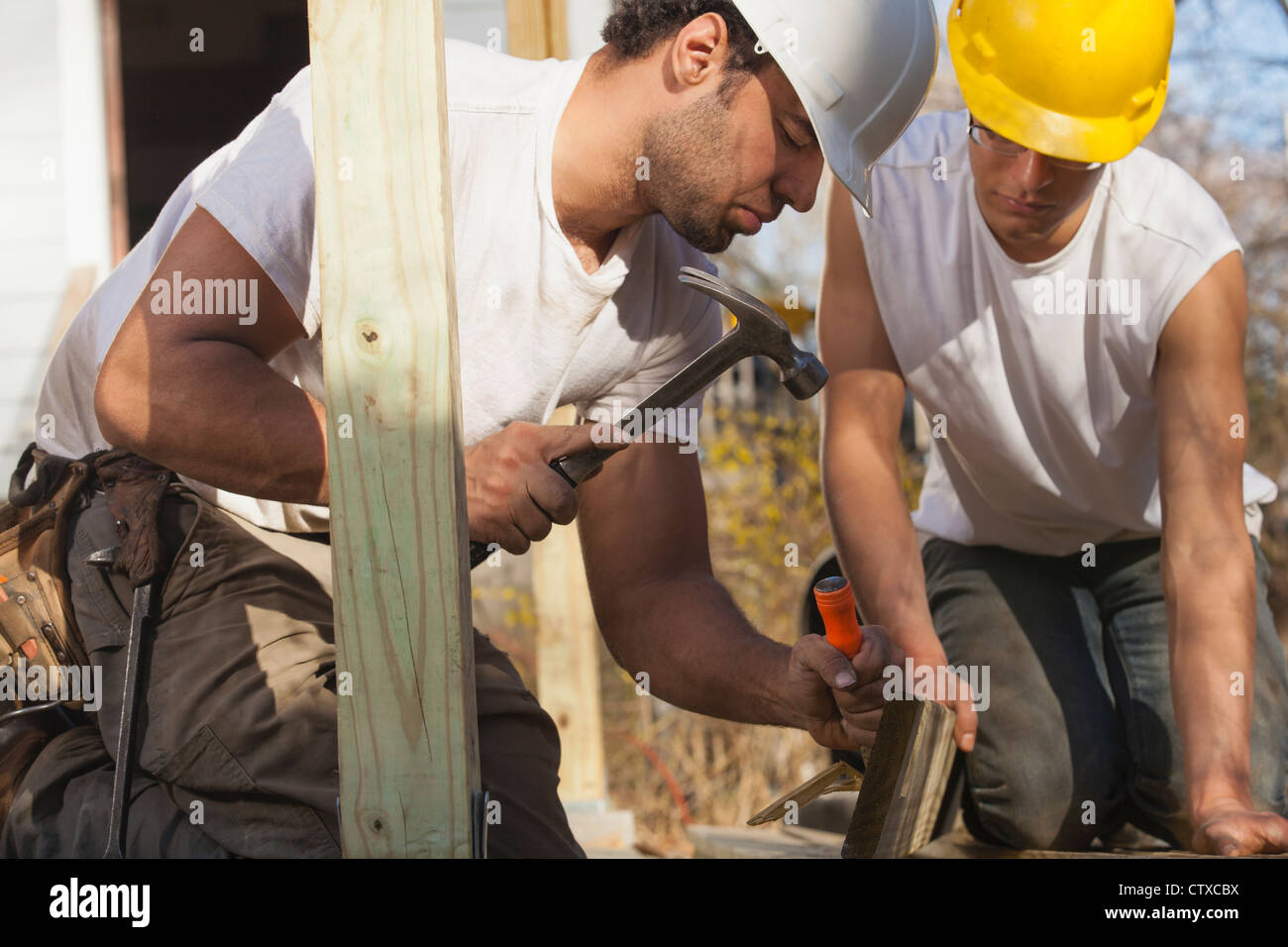 Hispanic carpenters using hammer and chisel on deck support Stock Photo ...