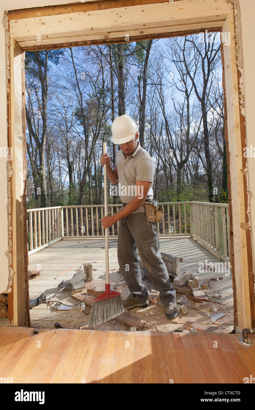 Hispanic carpenter cleaning newly cut door entrance from house to deck ...