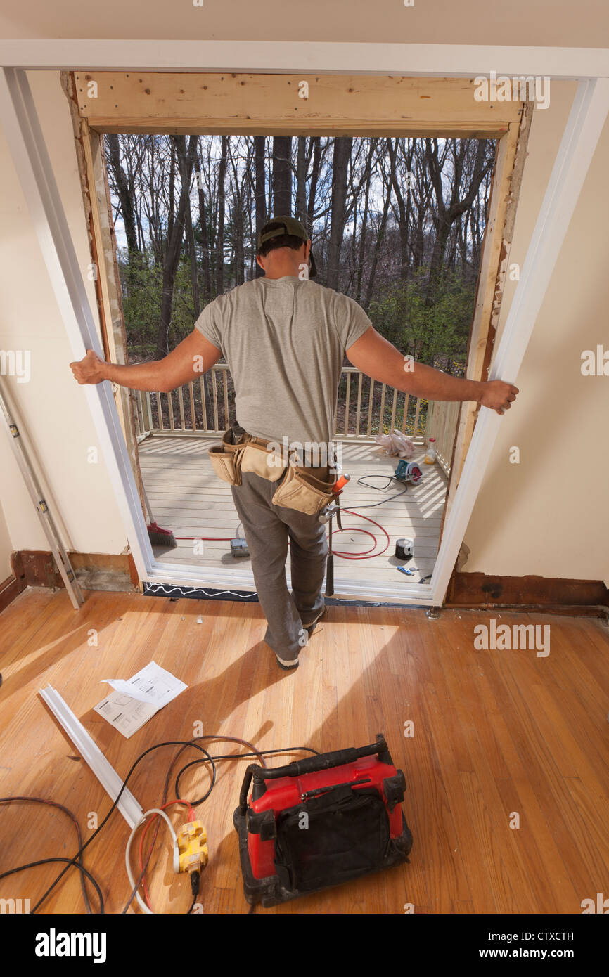 Hispanic carpenter fitting new door frame for access to new deck on ...