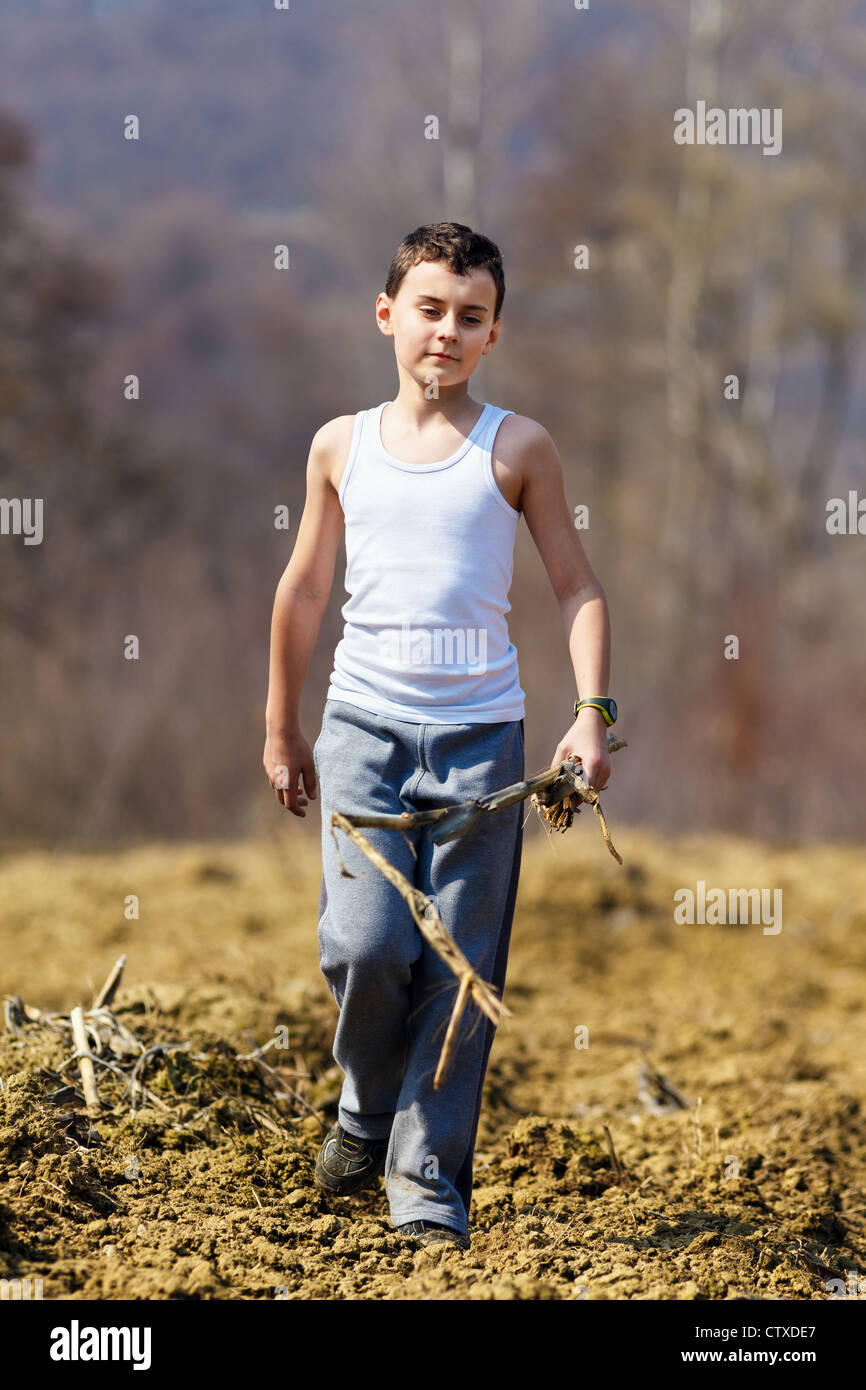 Kid walking on plowed soil holding a corn stalk Stock Photo - Alamy