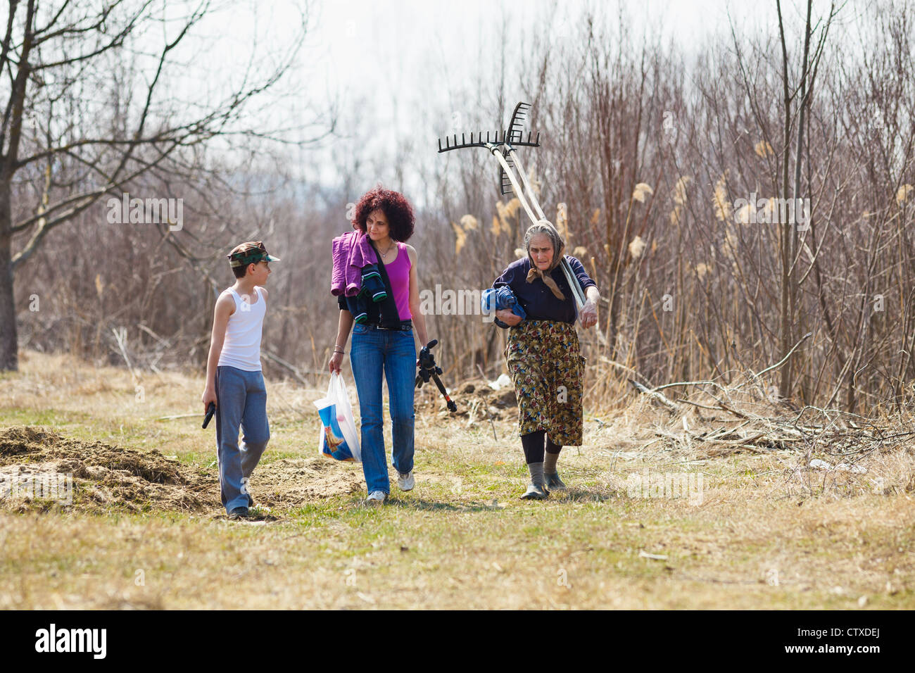 Son, mother and grandmother returning home from work in the field ...