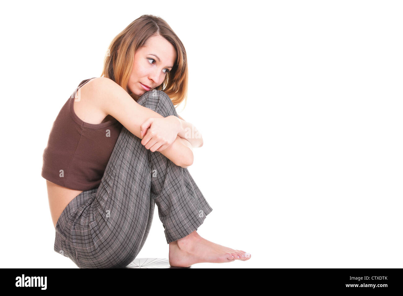 Portrait of young fit woman embracing her legs. Studio shot. Isolated ...