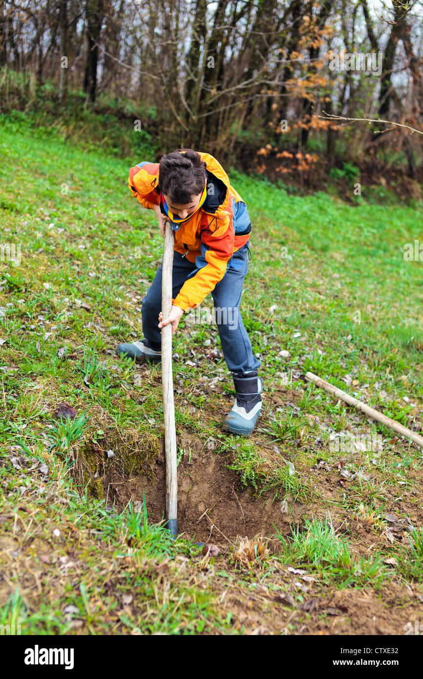 Boy digging on a grass field in the countryside Stock Photo - Alamy