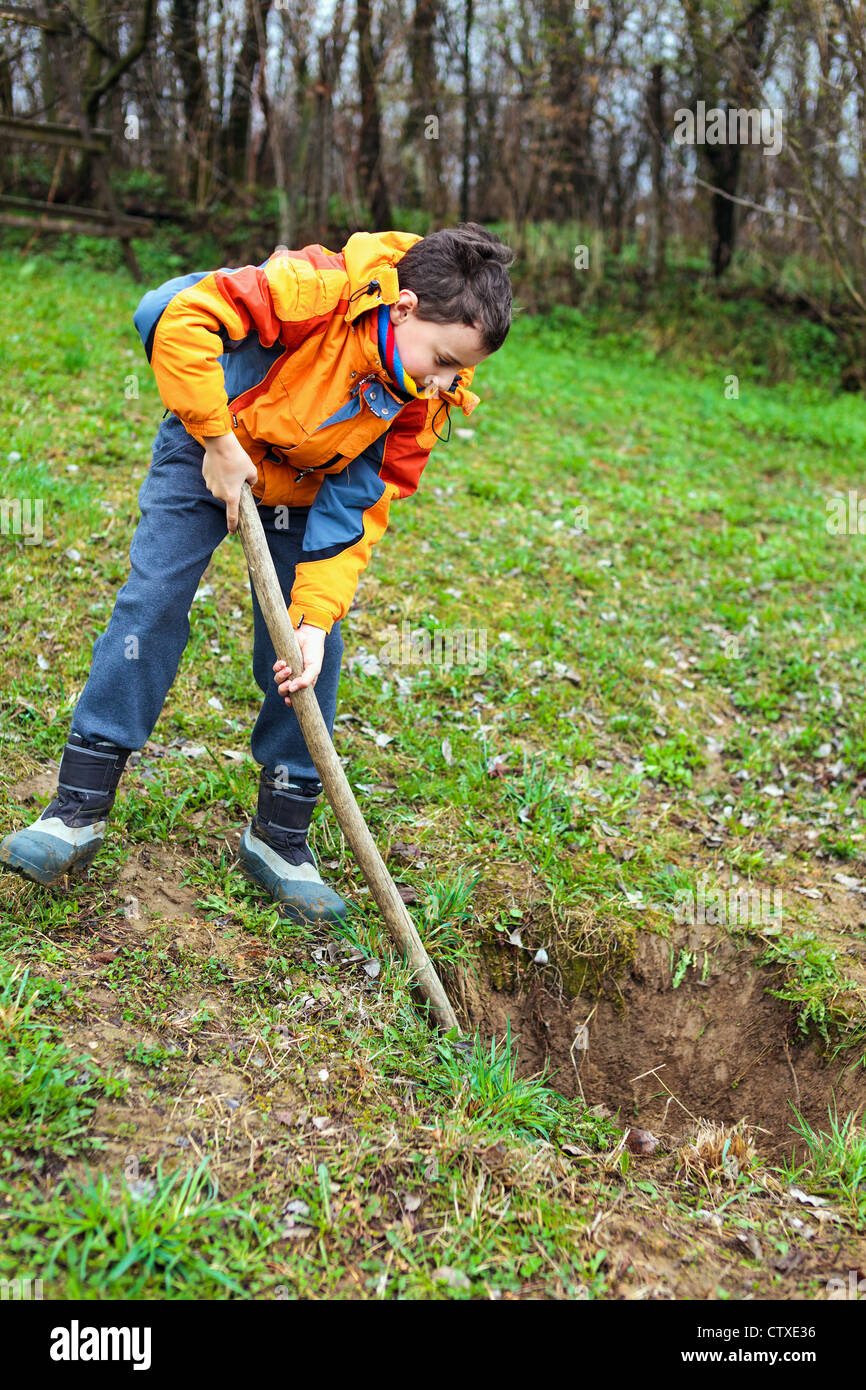 Boy digging on a grass field in the countryside Stock Photo - Alamy