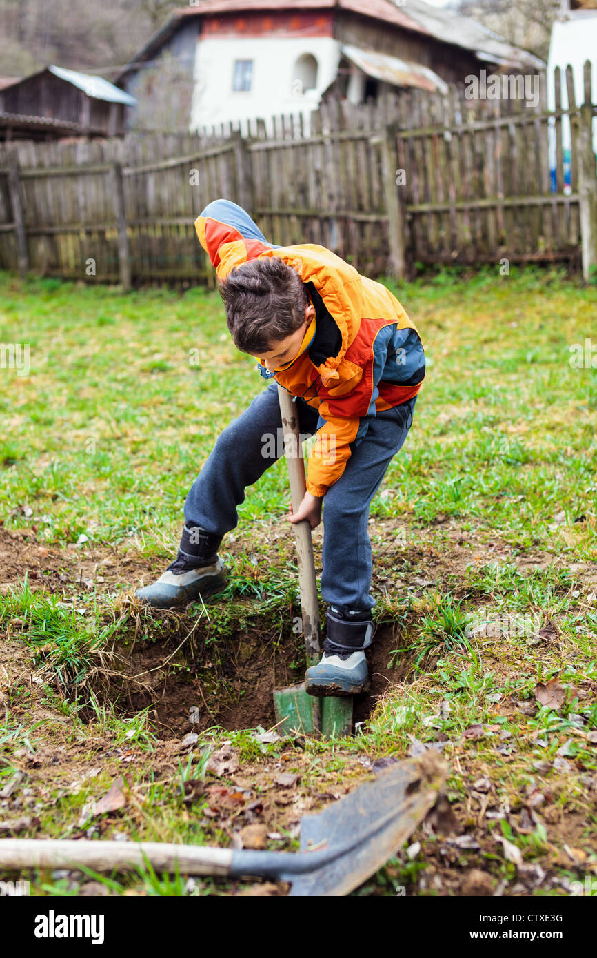 Boy digging on a grass field in the countryside Stock Photo - Alamy