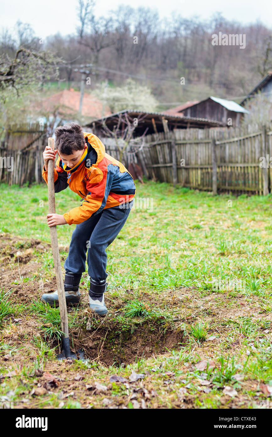Boy digging on a grass field in the countryside Stock Photo - Alamy