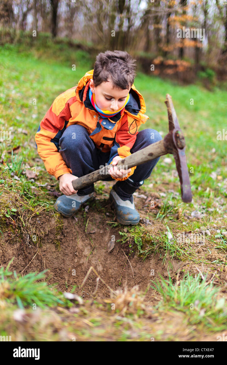 Boy digging on a grass field in the countryside Stock Photo - Alamy