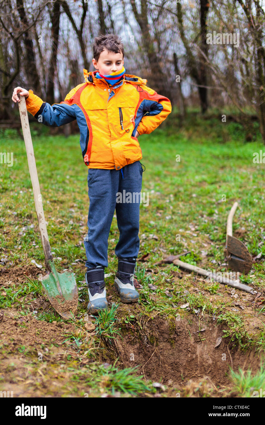 Boy digging on a grass field in the countryside Stock Photo - Alamy