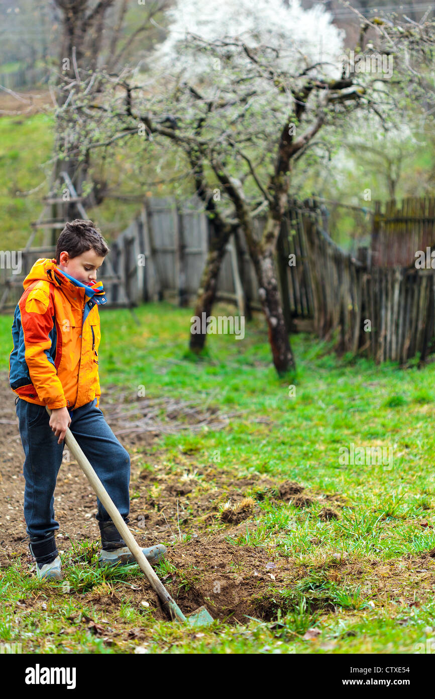 Boy digging on a grass field in the countryside Stock Photo - Alamy