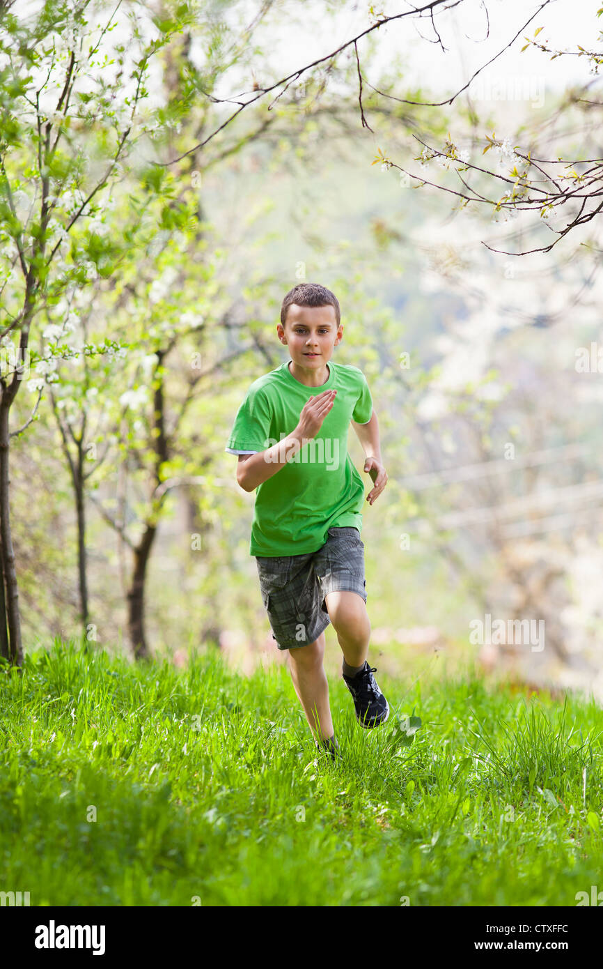 Boy running in a park or garden among trees Stock Photo - Alamy
