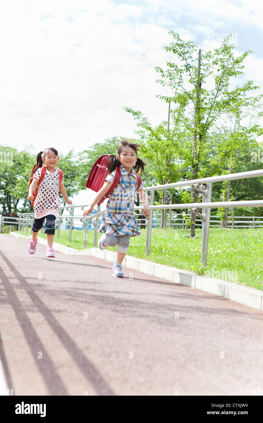 Two school girls running with backpack Stock Photo - Alamy