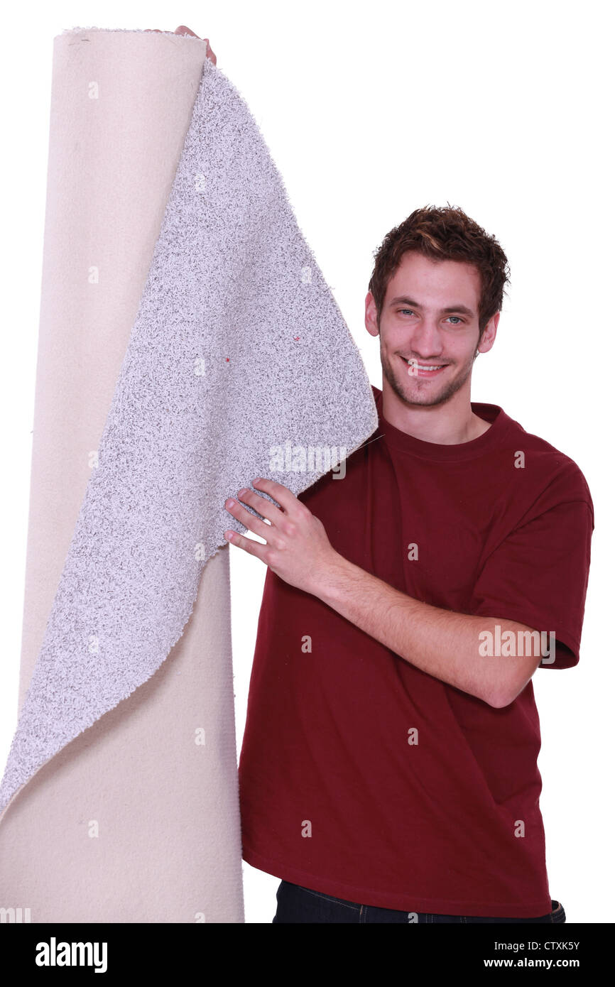 Young man standing with roll of carpet Stock Photo - Alamy