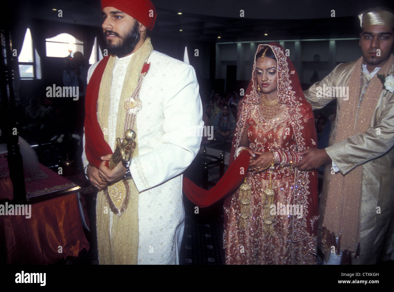 Sikh nuptials with husband and wife walking around the palki. She holds ...