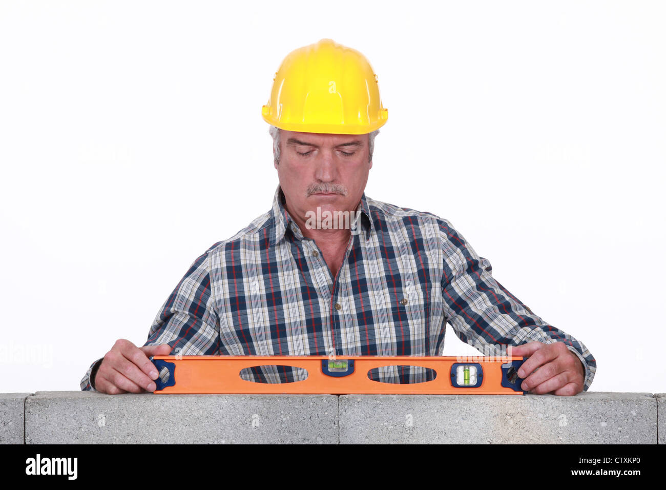 Experienced mason checking wall is level Stock Photo - Alamy
