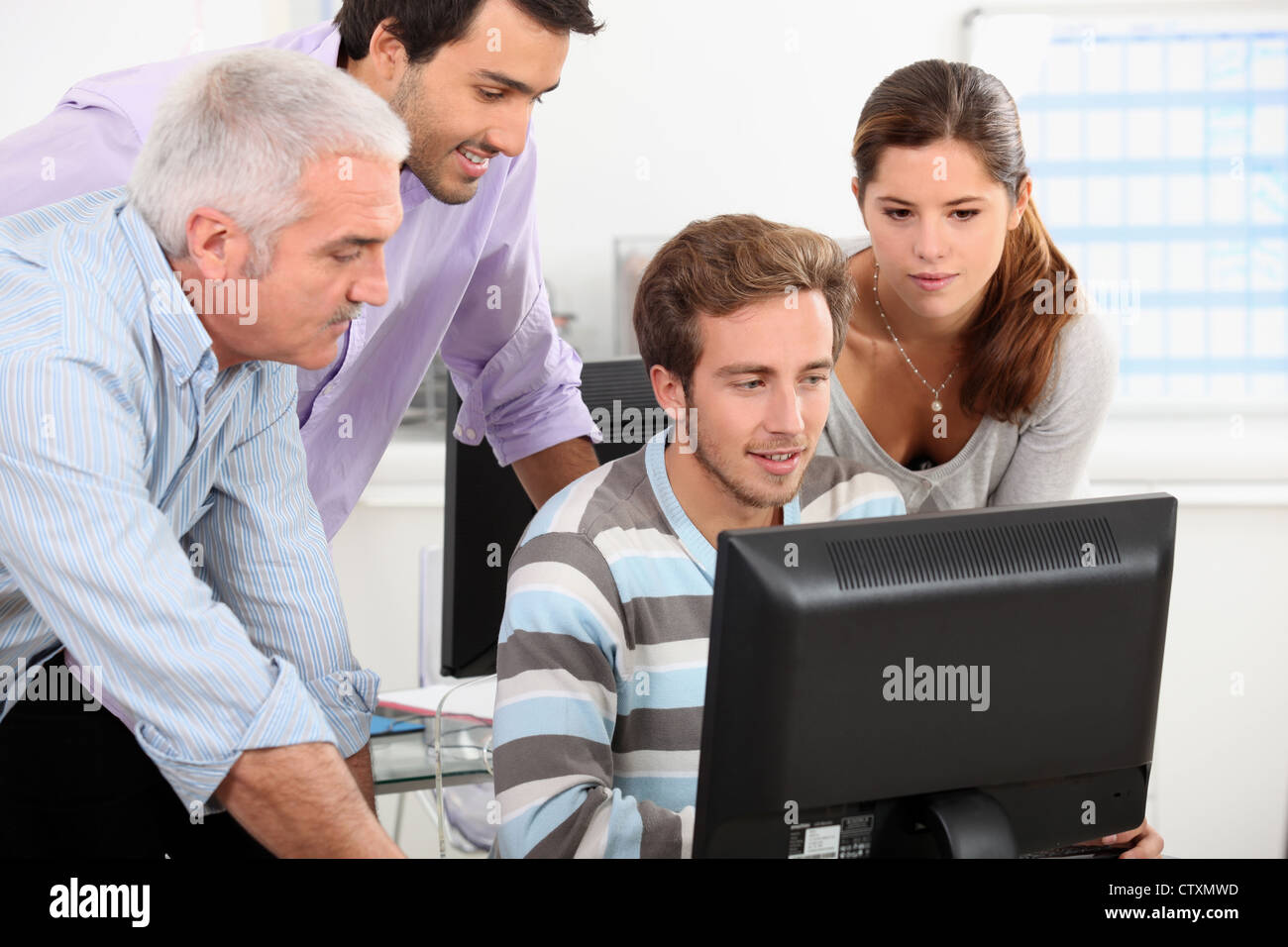 Colleagues around computer Stock Photo - Alamy