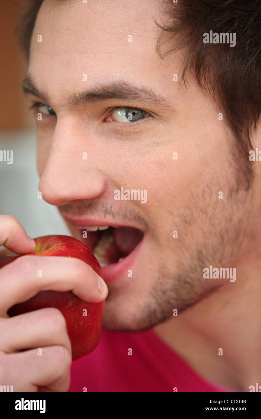 Young man biting into red apple Stock Photo - Alamy
