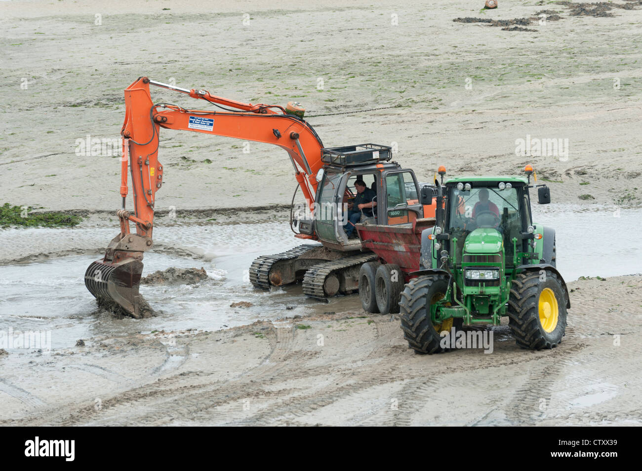Tractors and machinery digging or mining sea sand in Padstow harbour ...