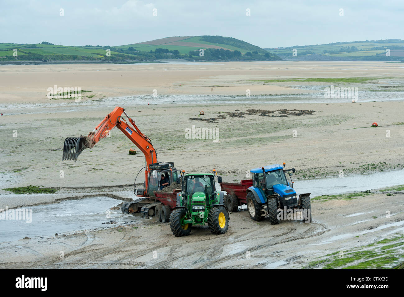 Tractors and machinery digging or mining sea sand in Padstow harbour ...