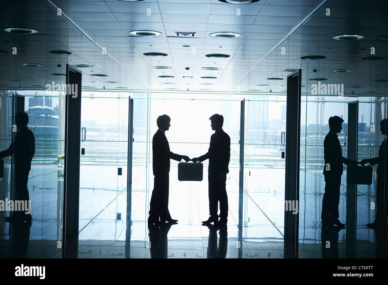 Businessmen handing over the briefcase in the hallway Stock Photo - Alamy